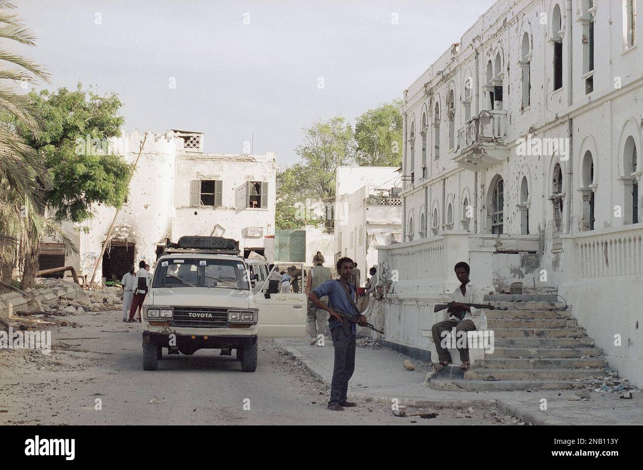Armed men walks in a bullet hole ridden street in Mogadishu, Somalia in ...