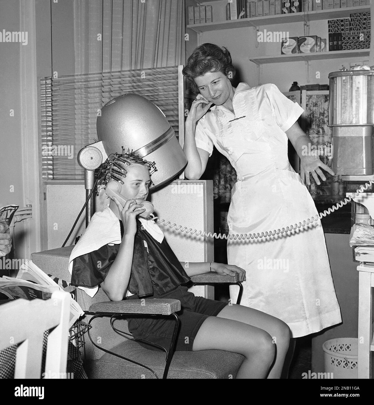 Hair stylist Pansy Phagan cools her heels as customer Dianne Hill uses the telephone in the ...