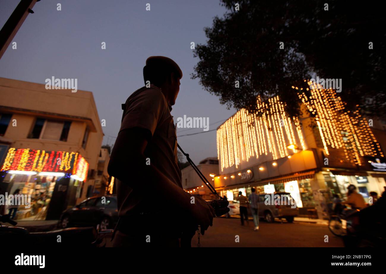 An Indian Police commando stands guard at a market where shops are ...