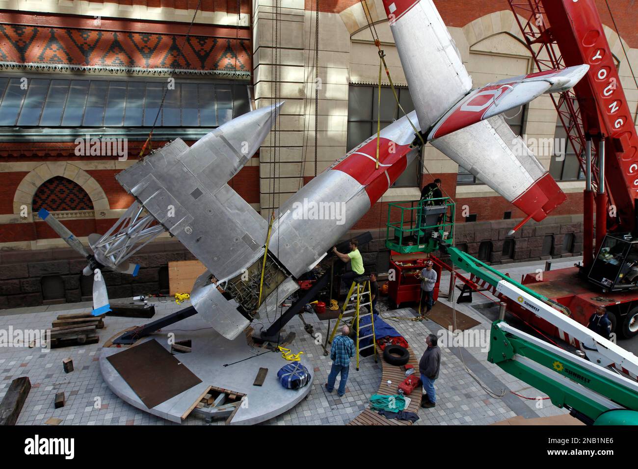 Artist Jordan Griska, center in green shirt, works to install his ...