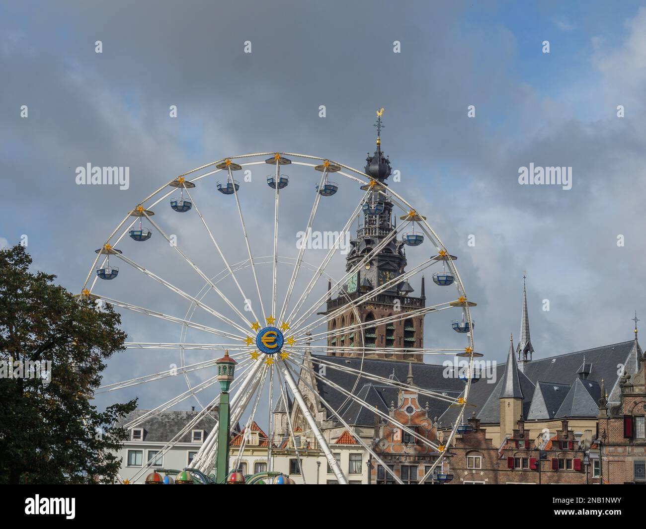 An old cathedral behind a Ferris wheel under cloudy sky in the ...