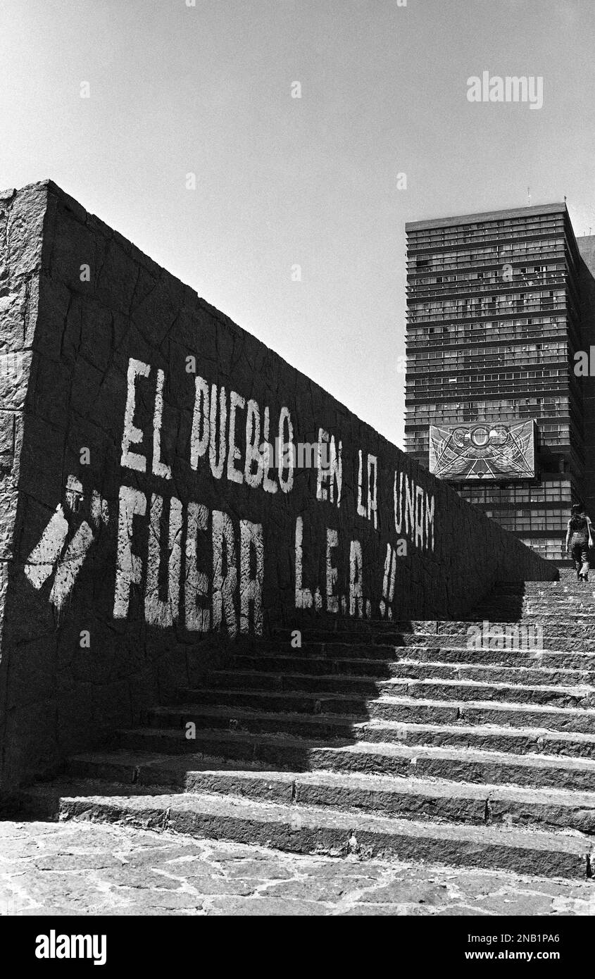 Two students walk hand in hand past a slogan painted on the wall of the ...