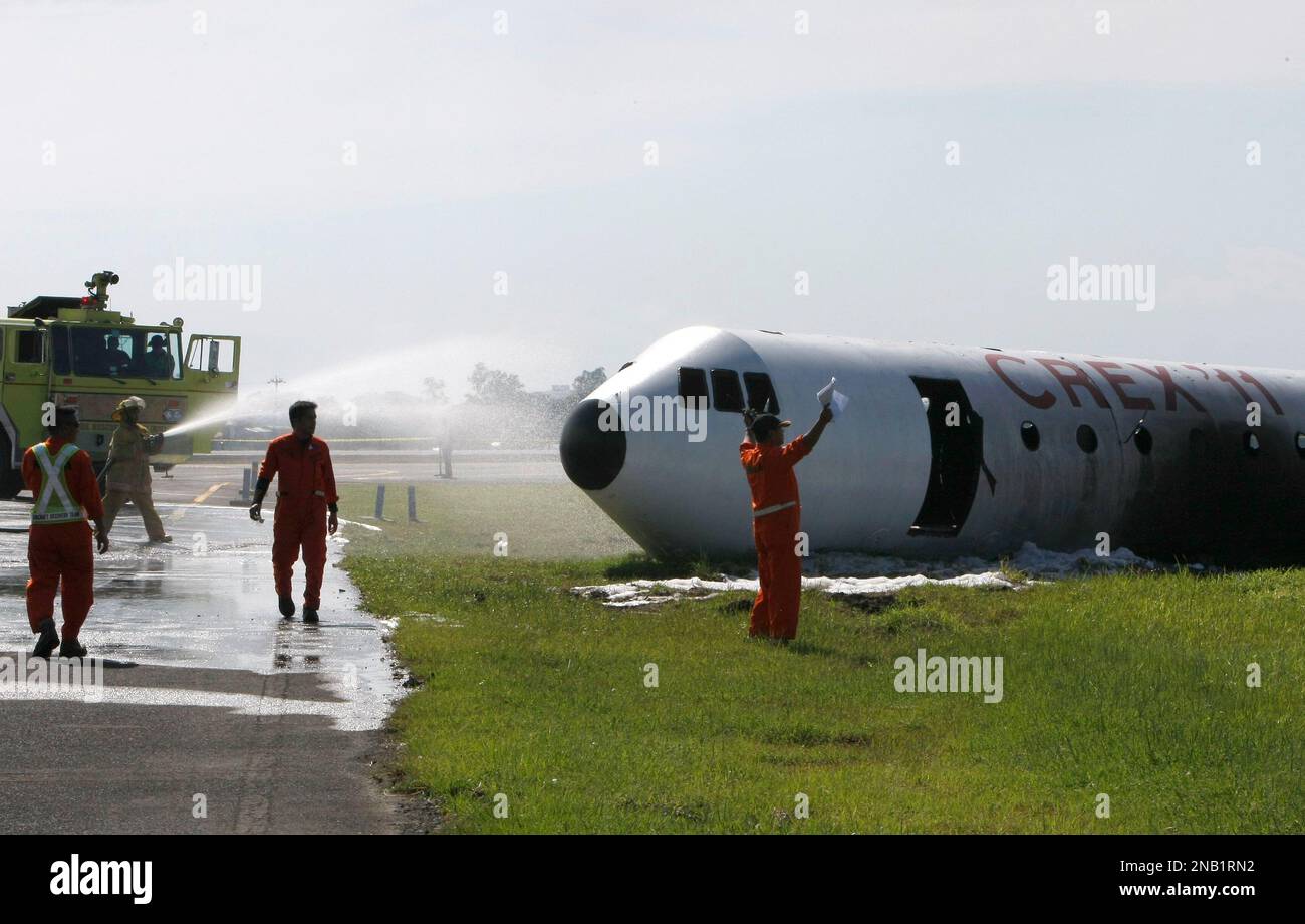 Firemen spray foam at a mock up model of a passenger plane during an ...