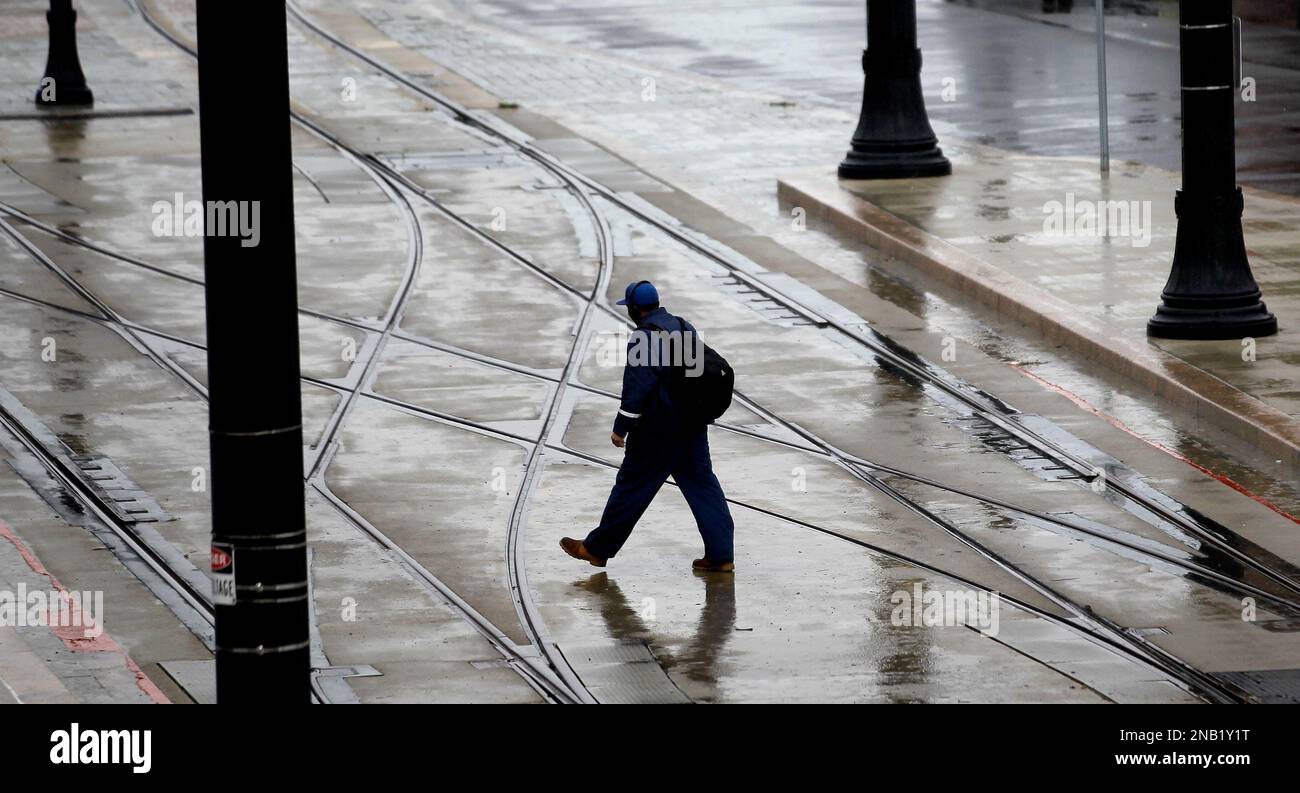 A man walks across light rail tracks following morning rain storms that ...