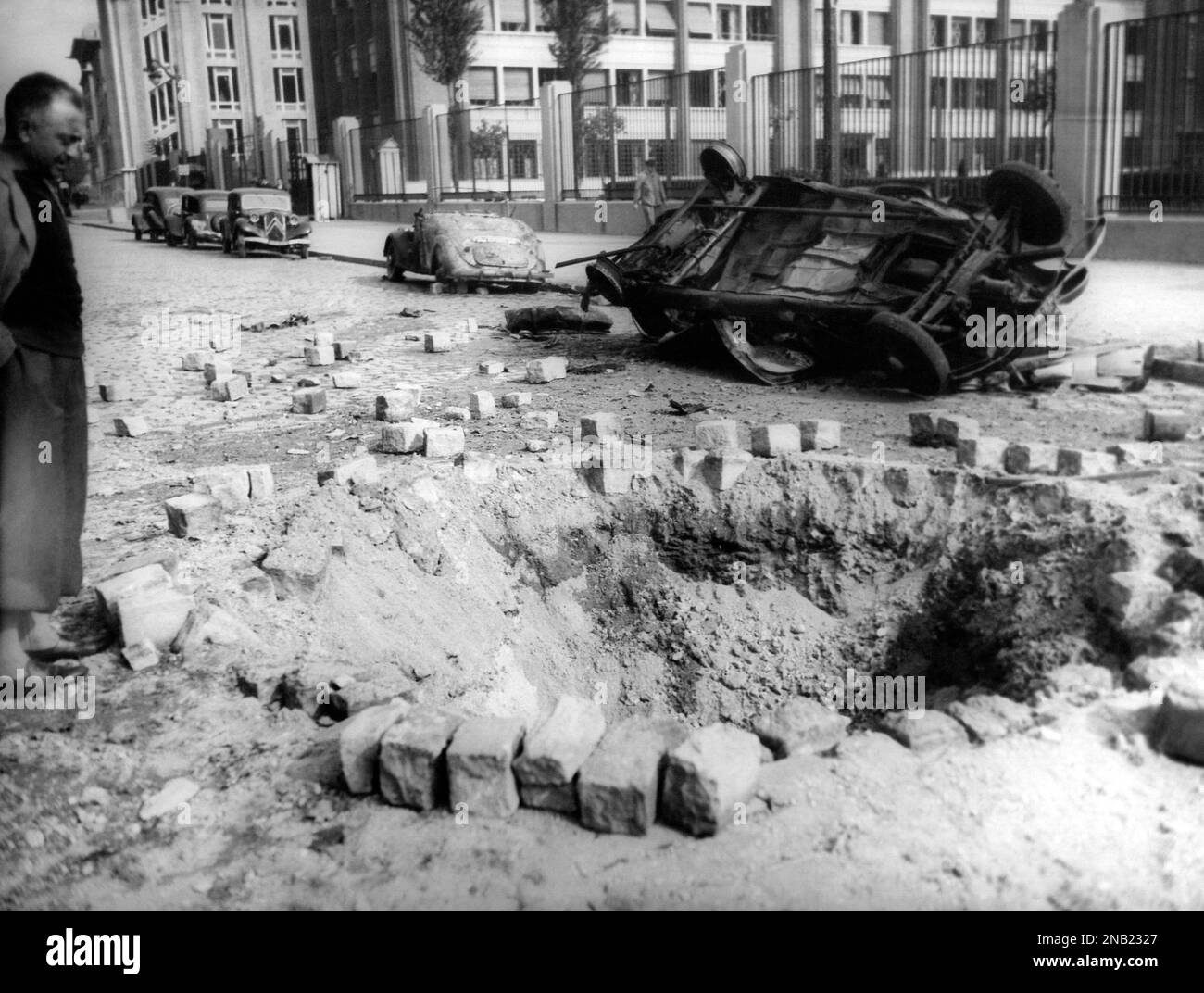 An upside down automobile, charred by a bomb, and the hole in the ...