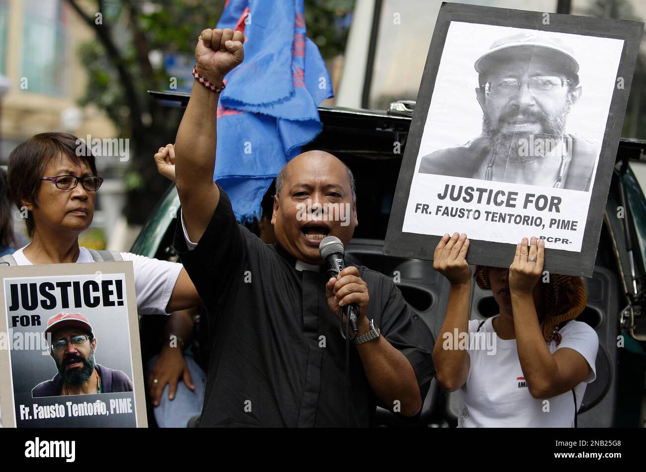 A Filipino Christian sect priest clenches his fist beside pictures of ...