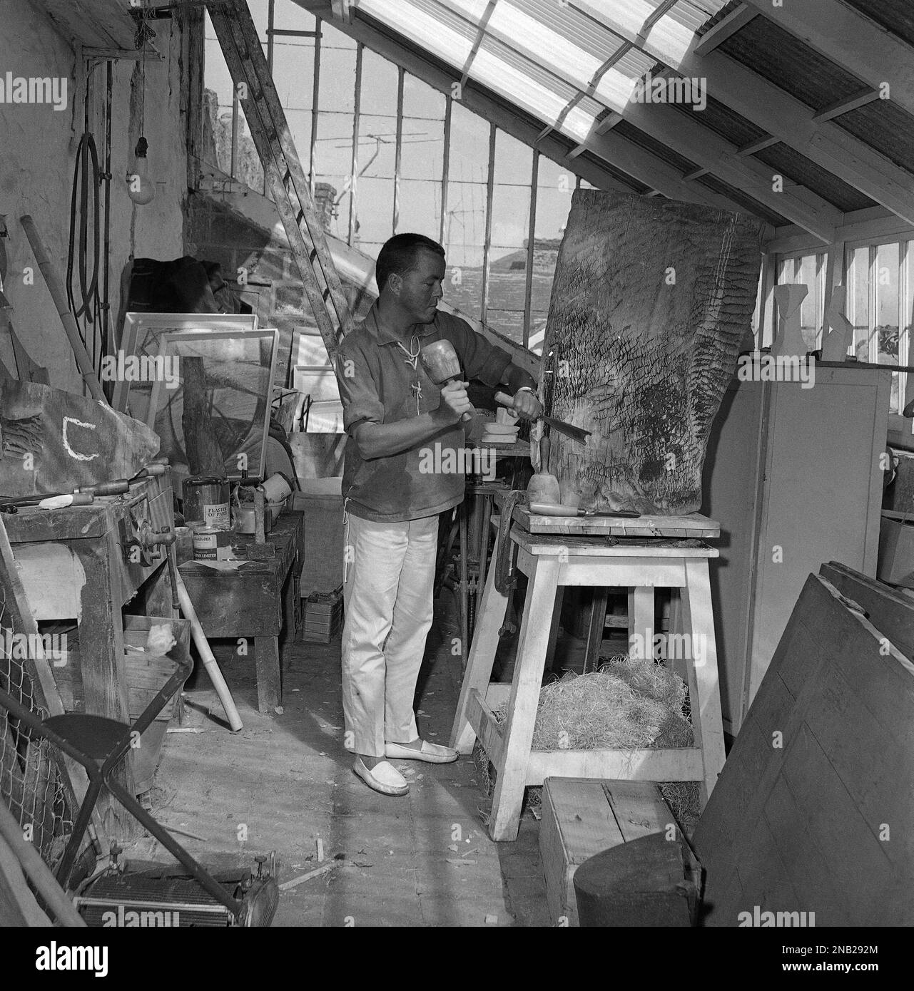 John Milne, 32-year-old British painter and sculptor, chisels away at a ...
