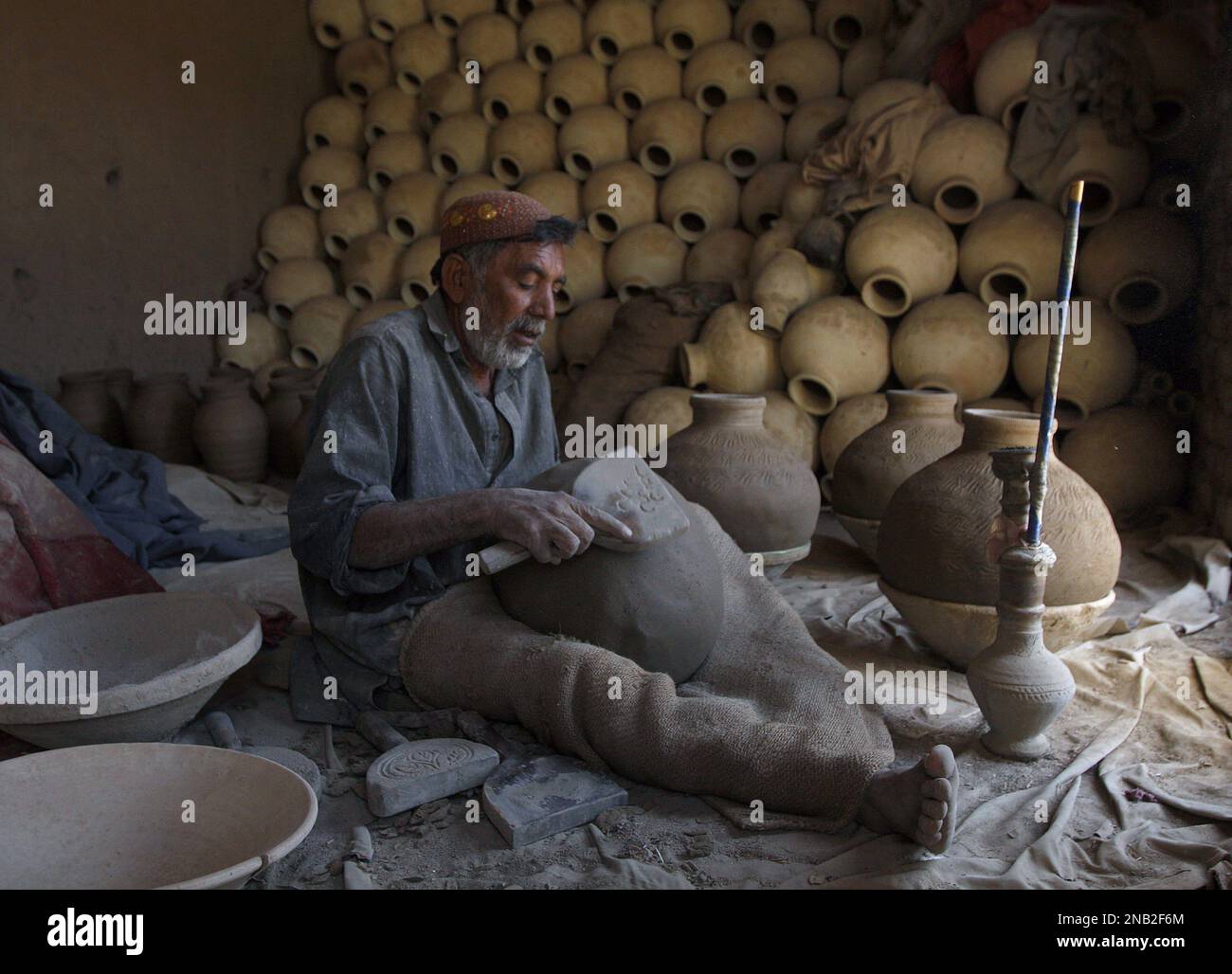 A Pakistani works to make clay pitchers at his workshop in Quetta ...
