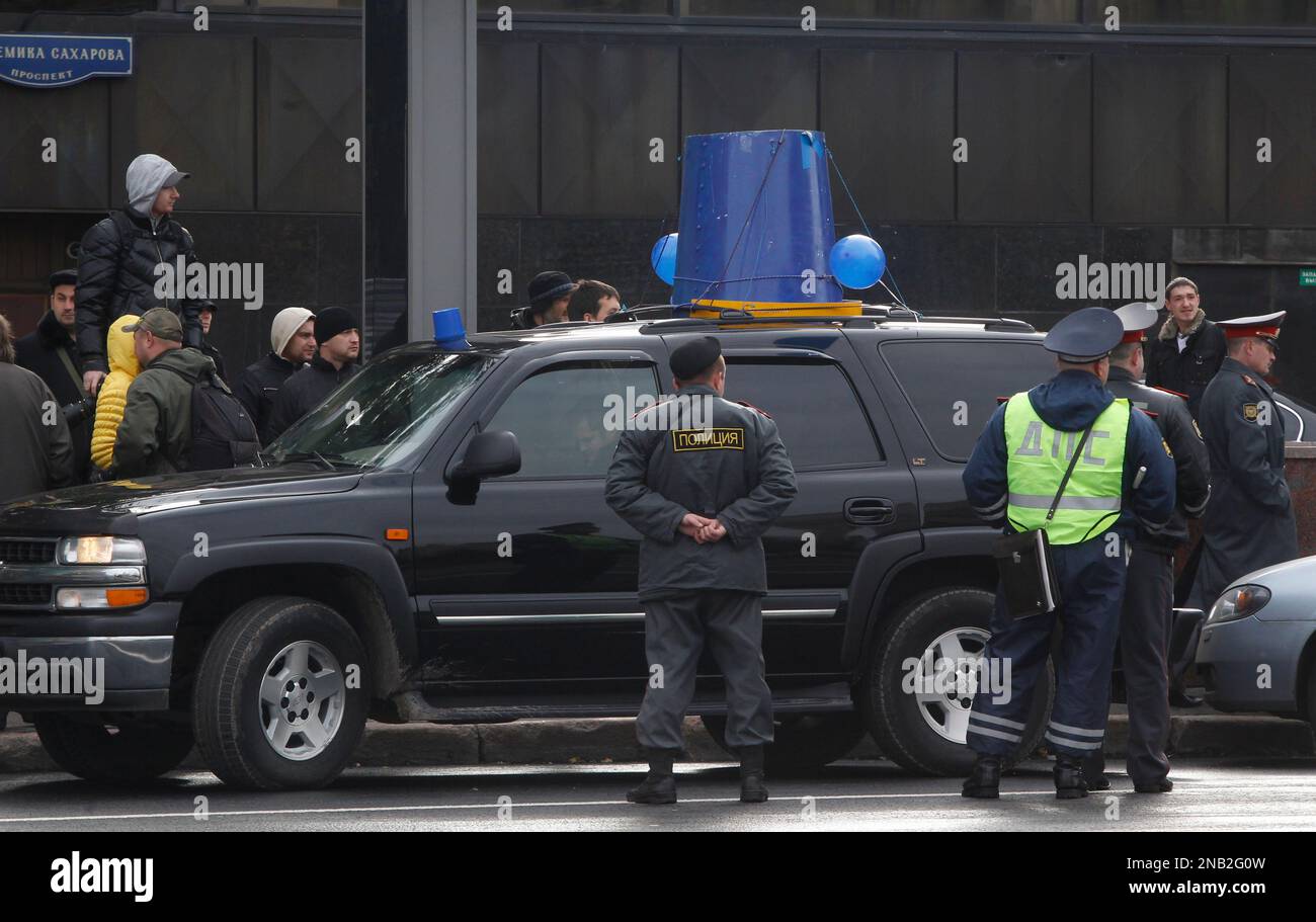 Police officers inspect a car with blue buckets strapped onto the roof ...