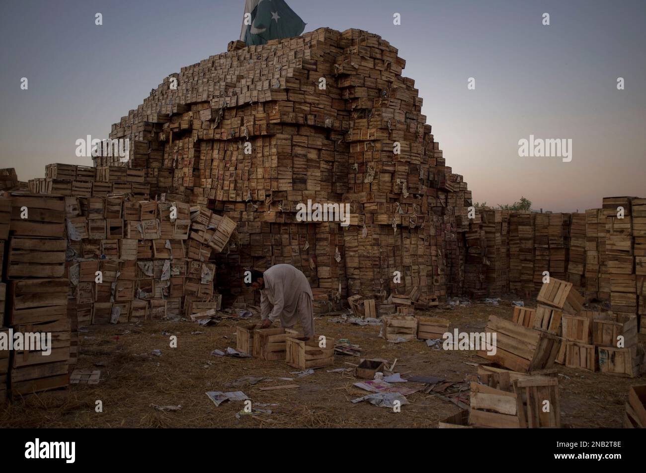 A Pakistani man recycles empty wooden cartons near a fruit and ...