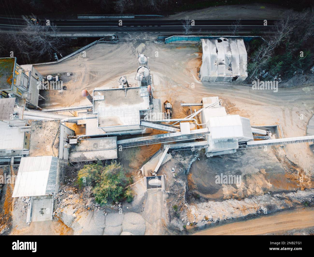 Dusty grounds at the small working quarry, heavy machinery and trucks ...
