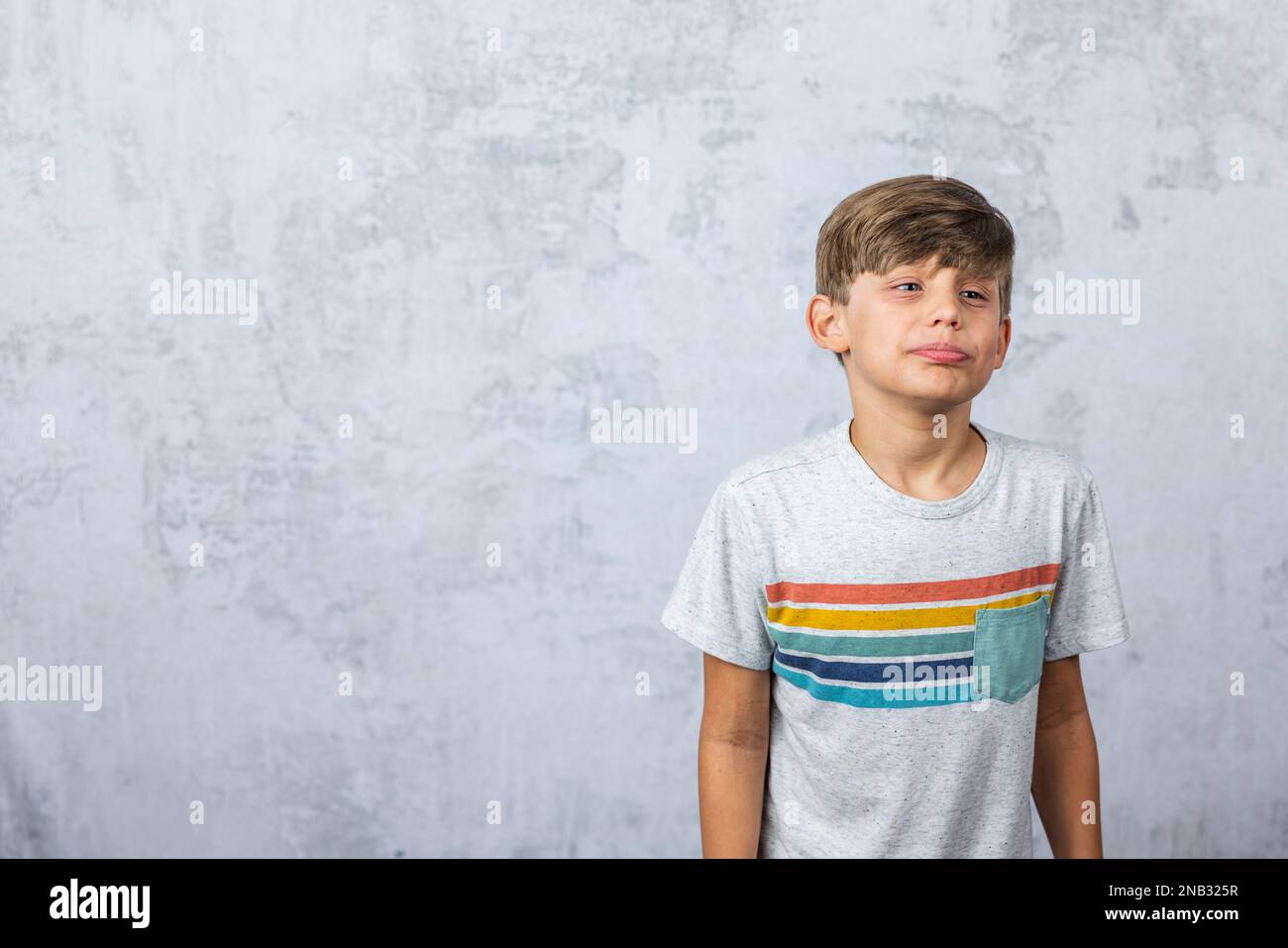 A cute little boy with autism in a studio setting making a pouty face ...