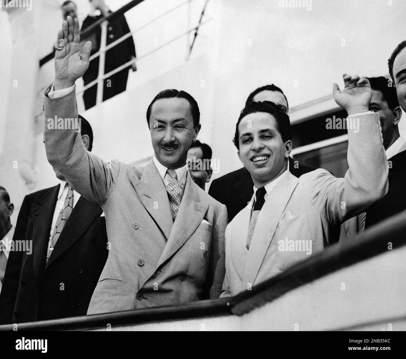 King Faisal II of Iraq (right), 17-year-old monarch, waves as he ...