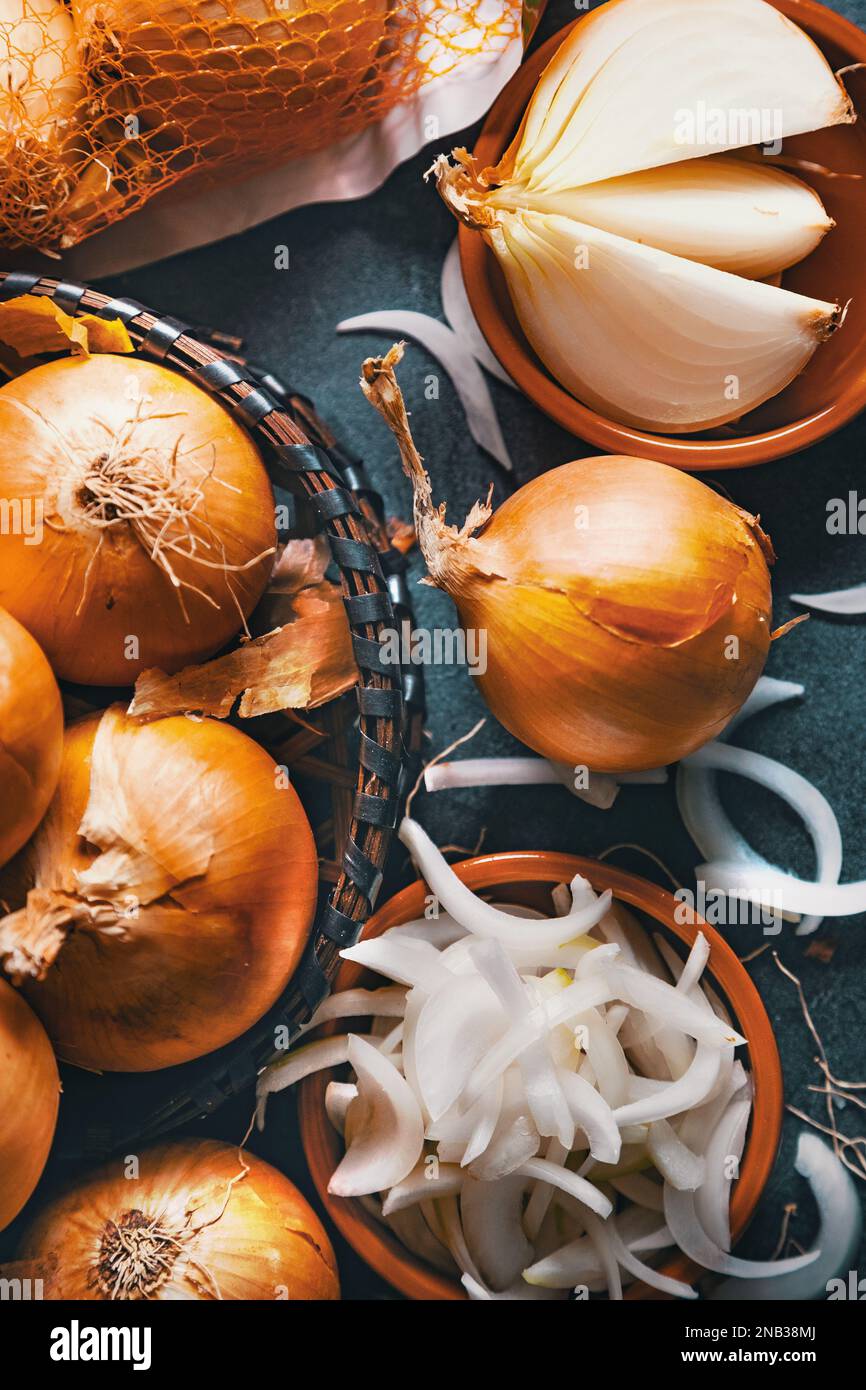 A lot of onions in a basket and plates on a dark and elegant dark ...