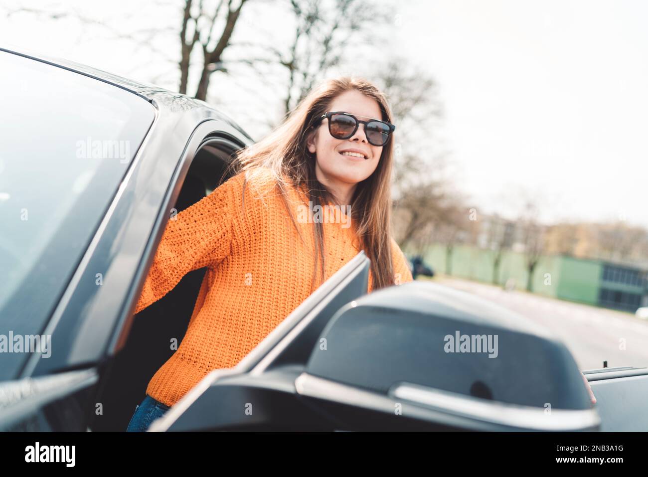 Young woman with long brown hair and big smile on her face stepping out ...