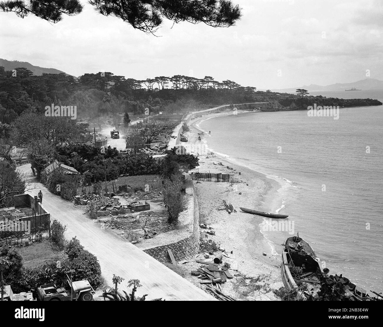 Scene of wrecked town with Japanese landing barges in foreground and ...