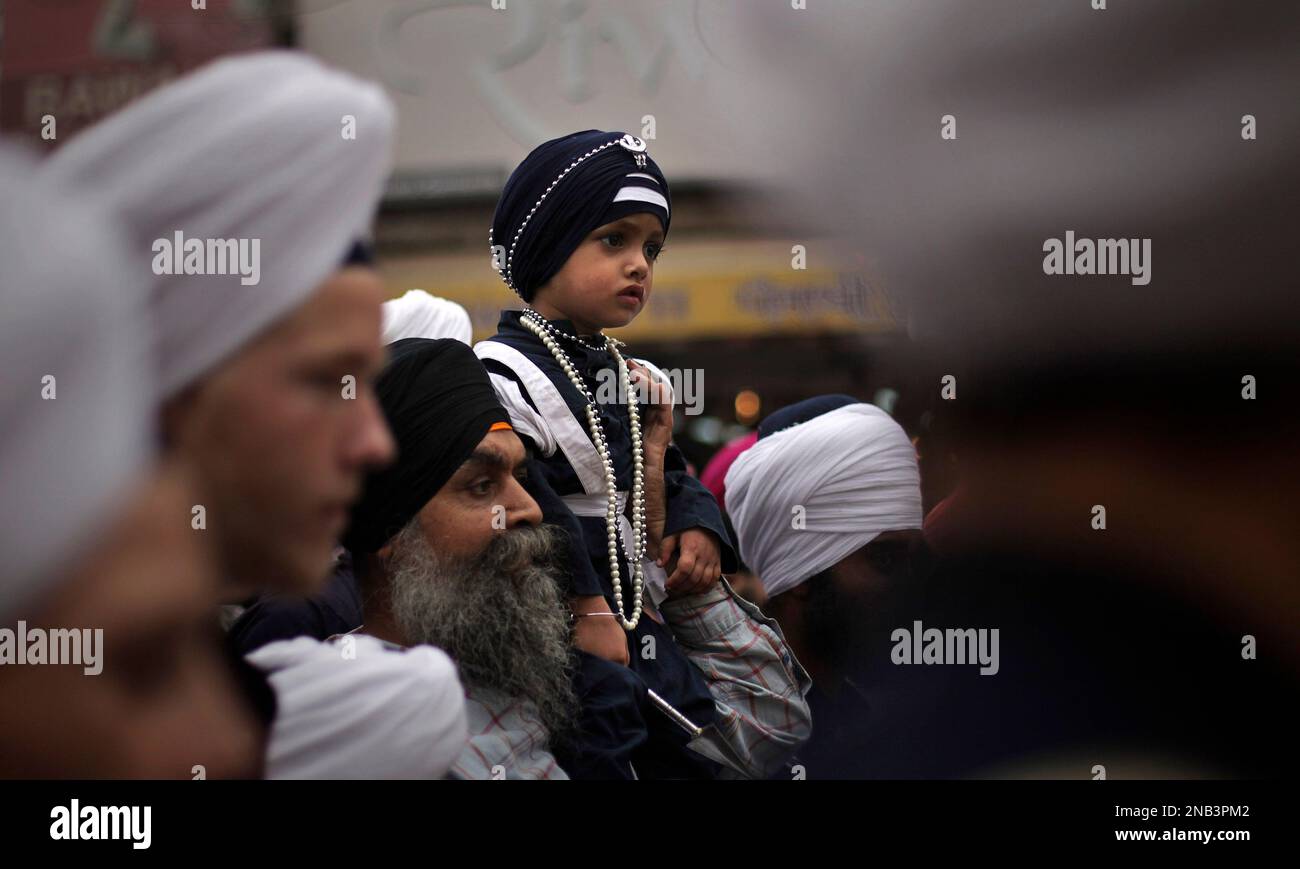 A young Sikh boy, dressed as a warrior, sits on the shoulder of his ...