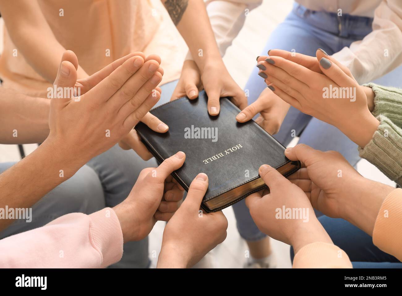 Group of people praying with Holy Bible in room, closeup Stock Photo ...