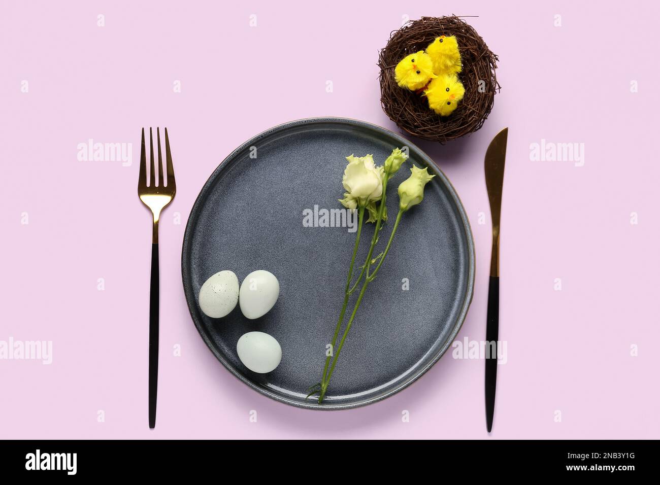 Table setting with Easter eggs, eustoma flowers and baby chickens in ...