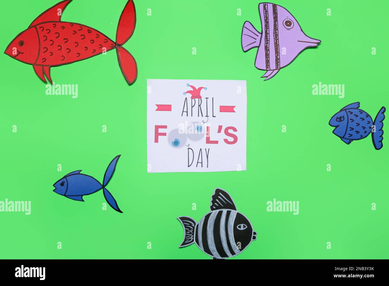 Card with text APRIL FOOL'S DAY and paper fishes on green background ...