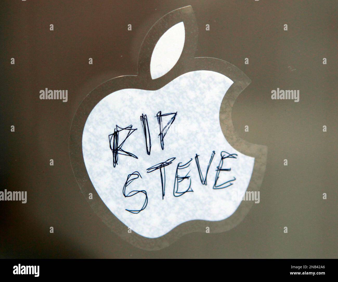 A condolence message on an Apple logo sticker adheres to the window of ...