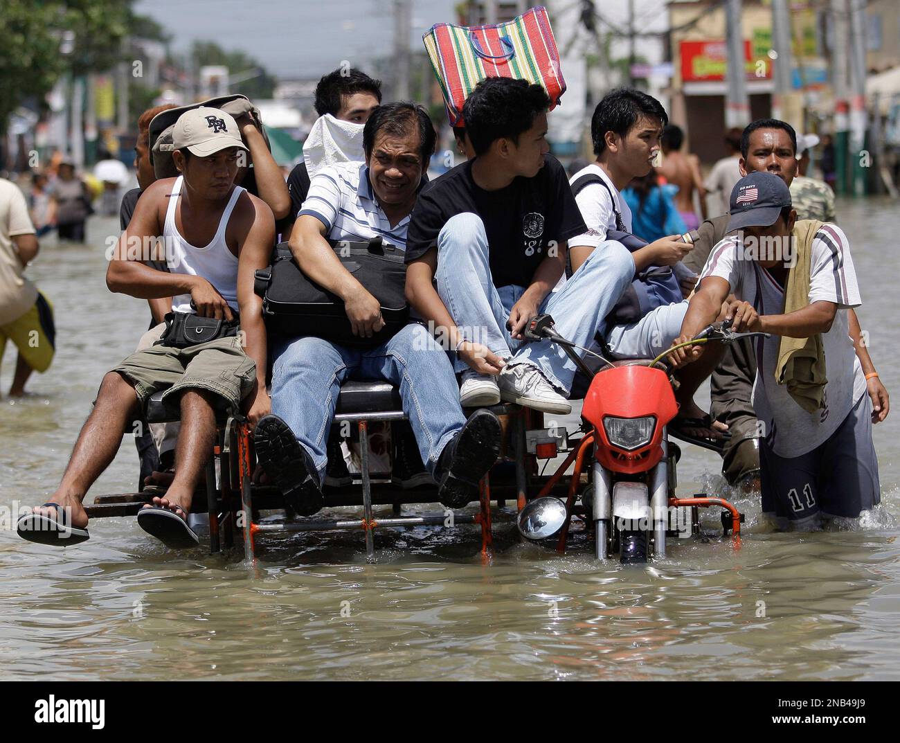 Residents ride a tricycle to keep dry as they cross a flood-hit area of ...