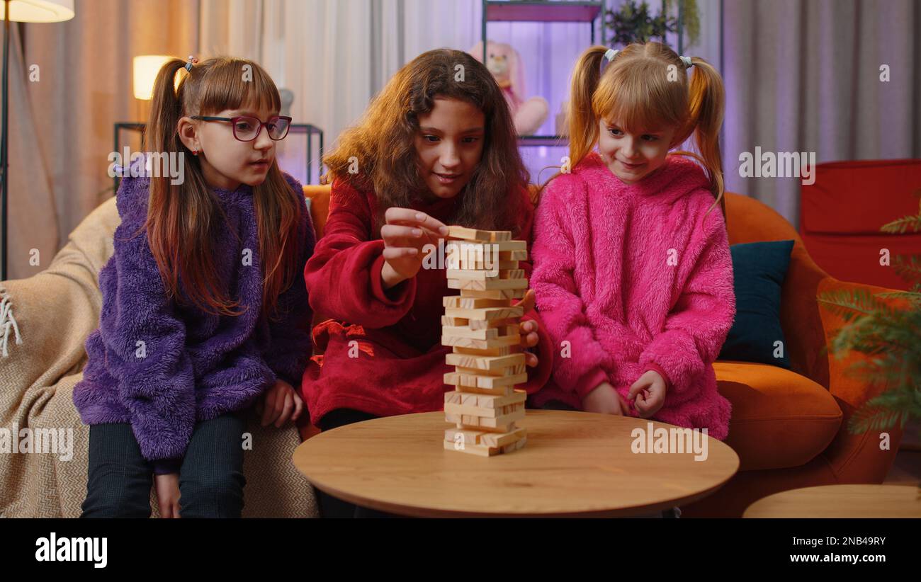 Teenage girl and toddler child sisters build tower from wooden bricks ...