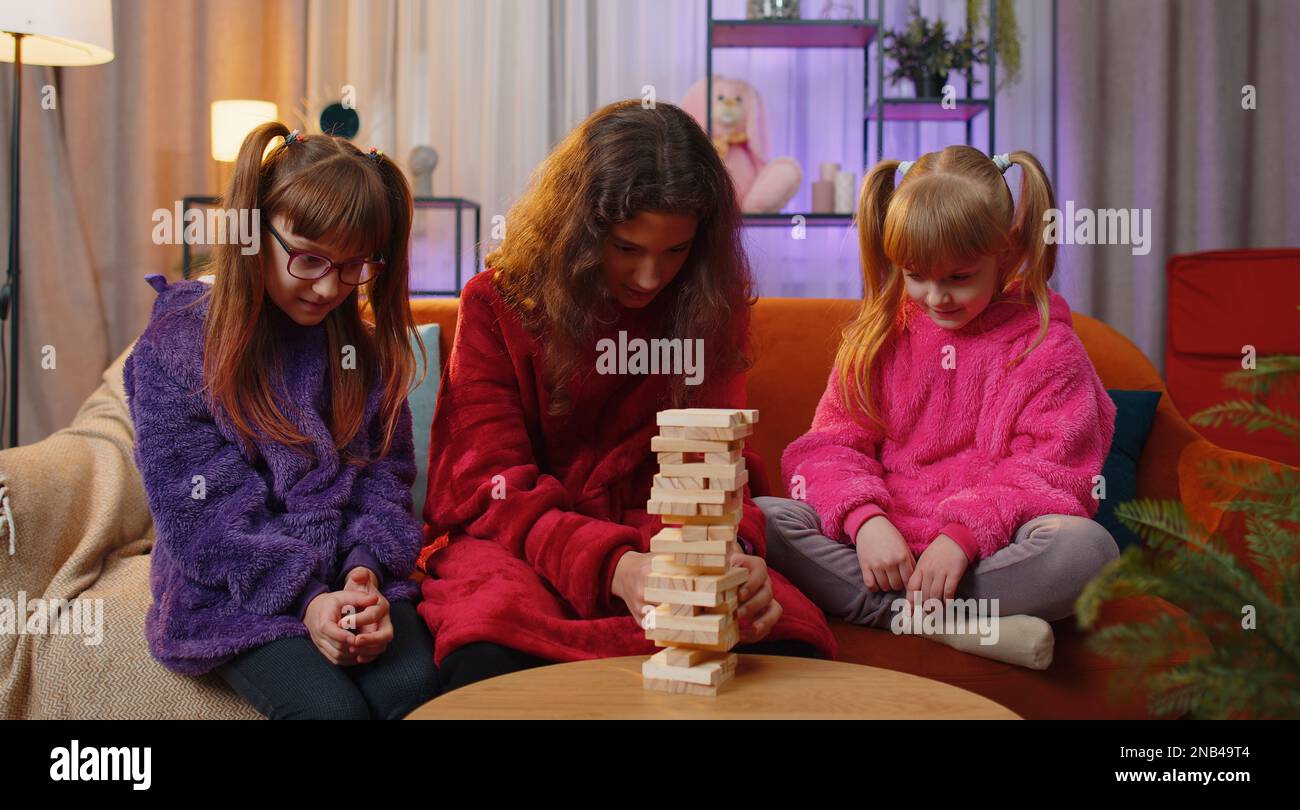 Teenage girl and toddler child sisters build tower from wooden bricks ...
