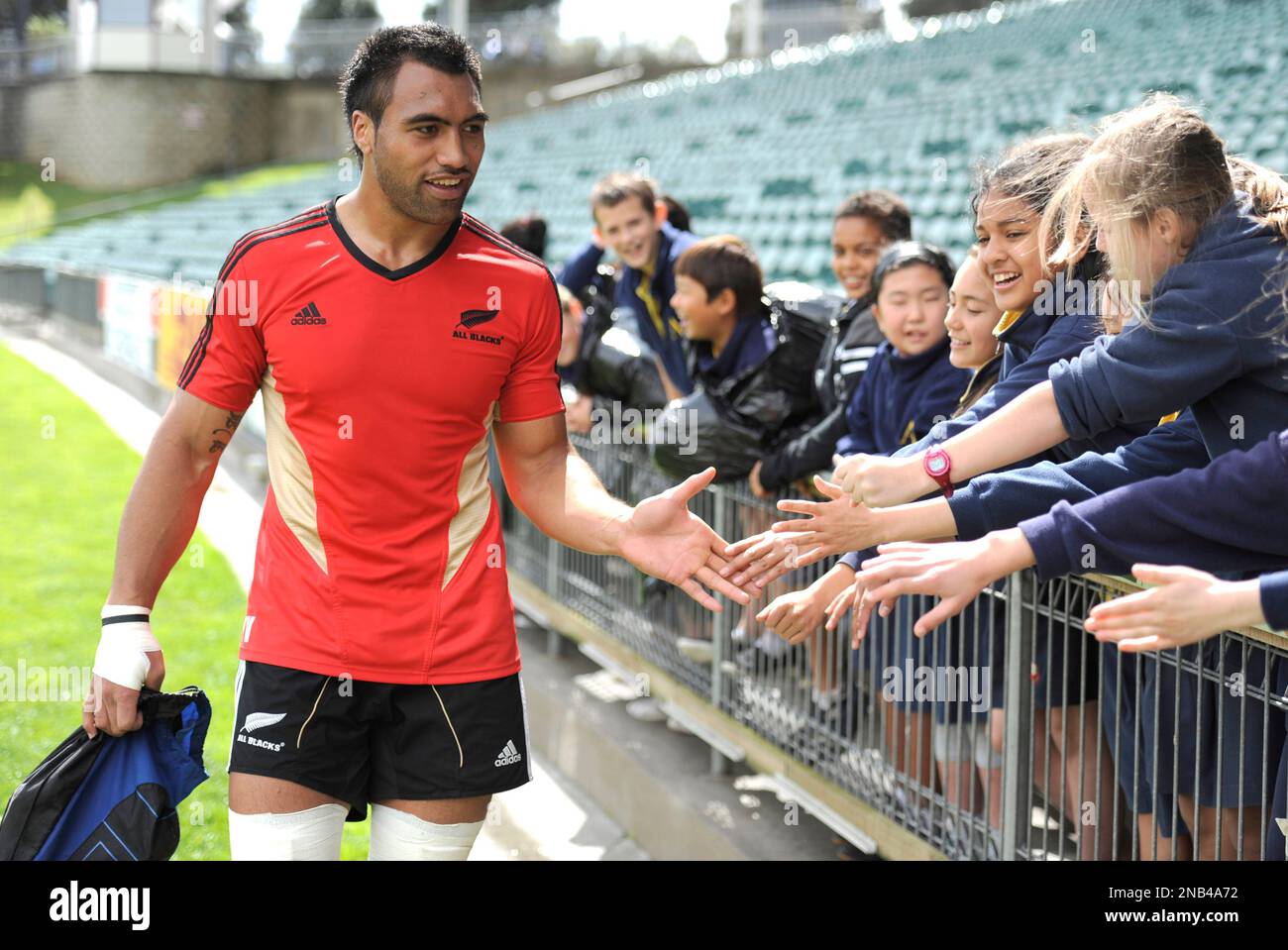 New Zealand rugby players Victor Vito shakes hands with school children ...