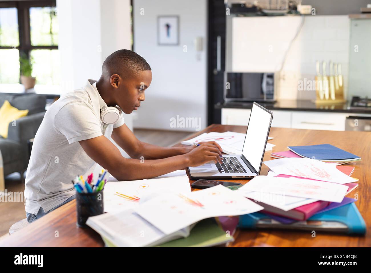 African american teenage boy using computer and doing lessons at home ...