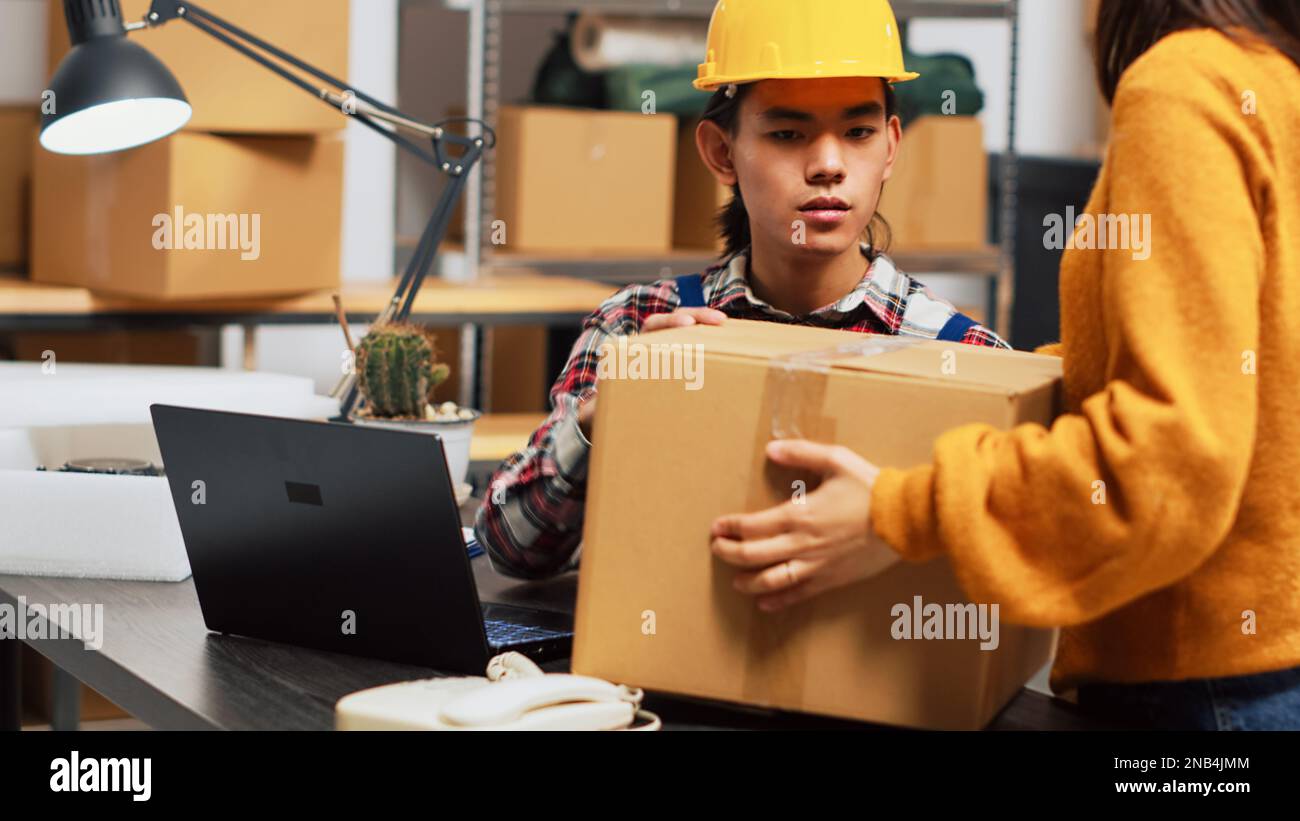 Young person doing warehouse inventory with pc, organizing products in ...