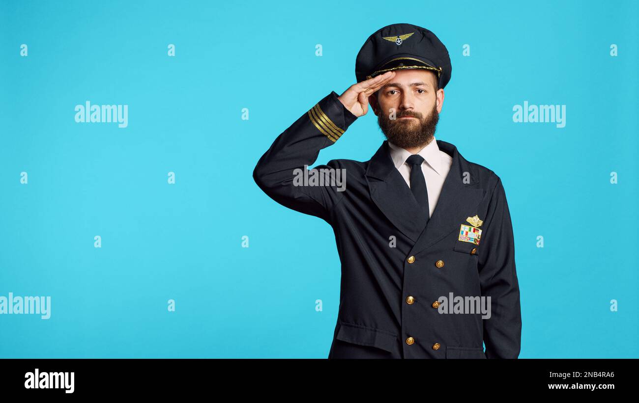 Male aviator doing military salute over blue backdrop, showing respect ...