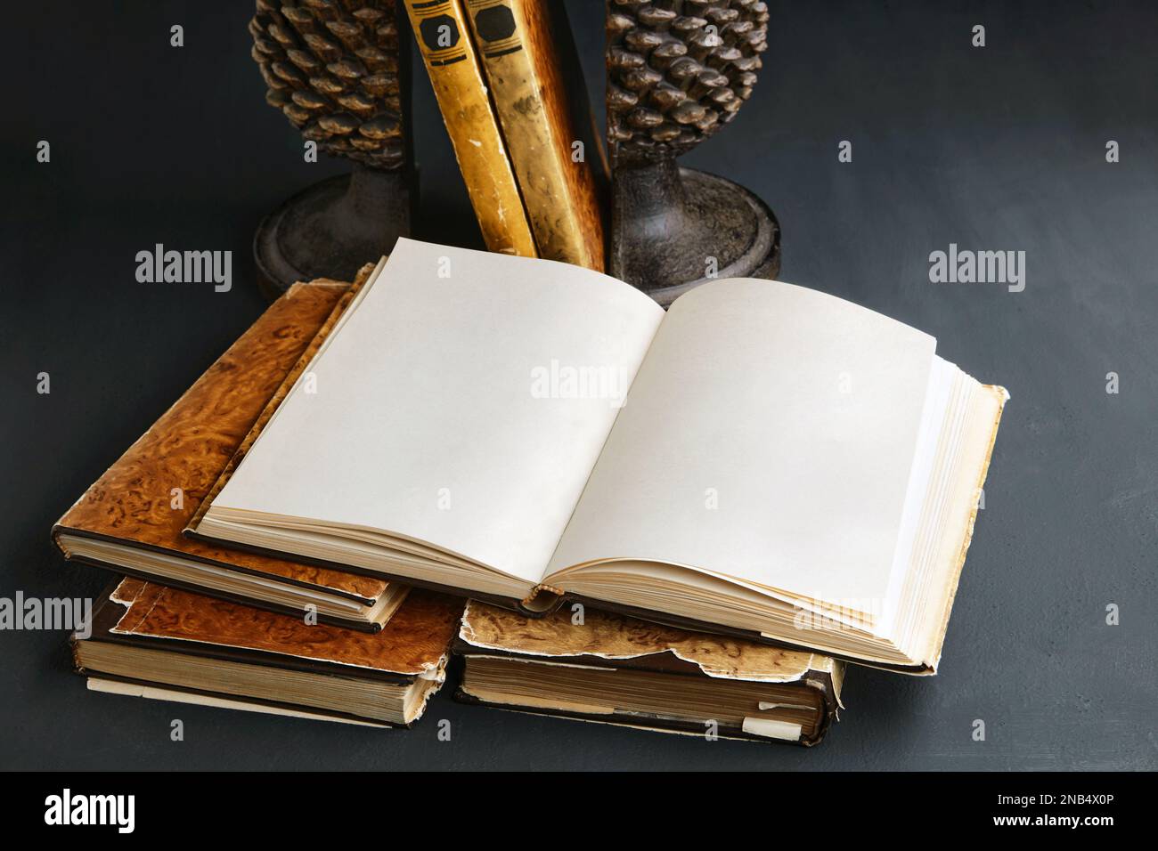 A shabby vintage book with blank pages on a stack of books on a black ...