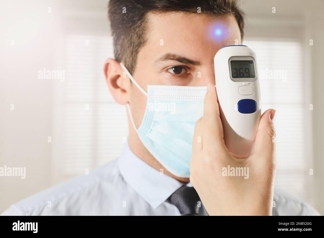 Doctor measuring man's temperature in office closeup. Prevent spreading ...