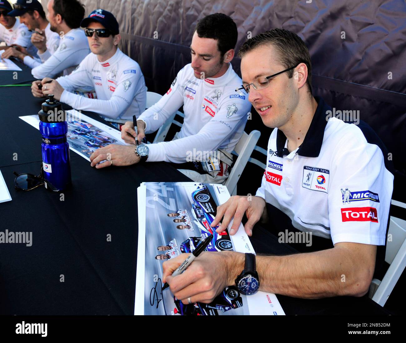 Peugeot driver Sebastien Bourdais, right, of France, signs a poster for ...