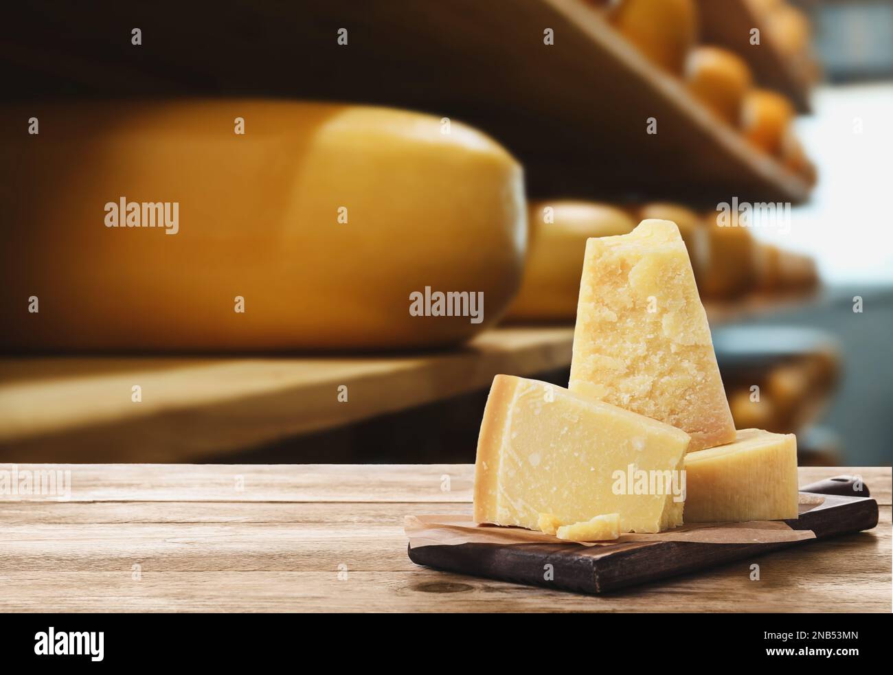 Delicious parmesan cheese on wooden table in warehouse, space for text ...