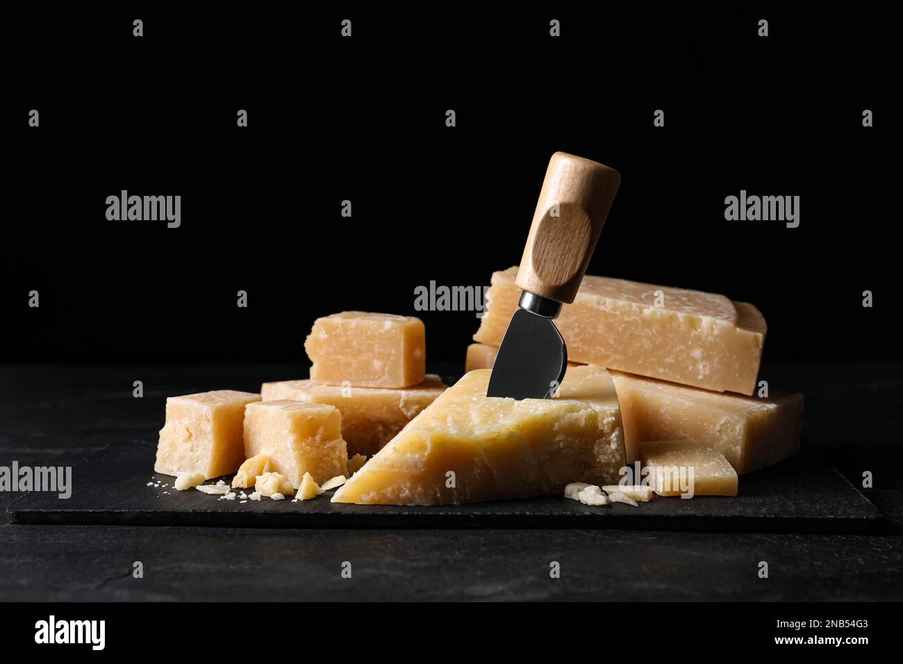 Parmesan cheese with slate plate and knife on black table Stock Photo ...