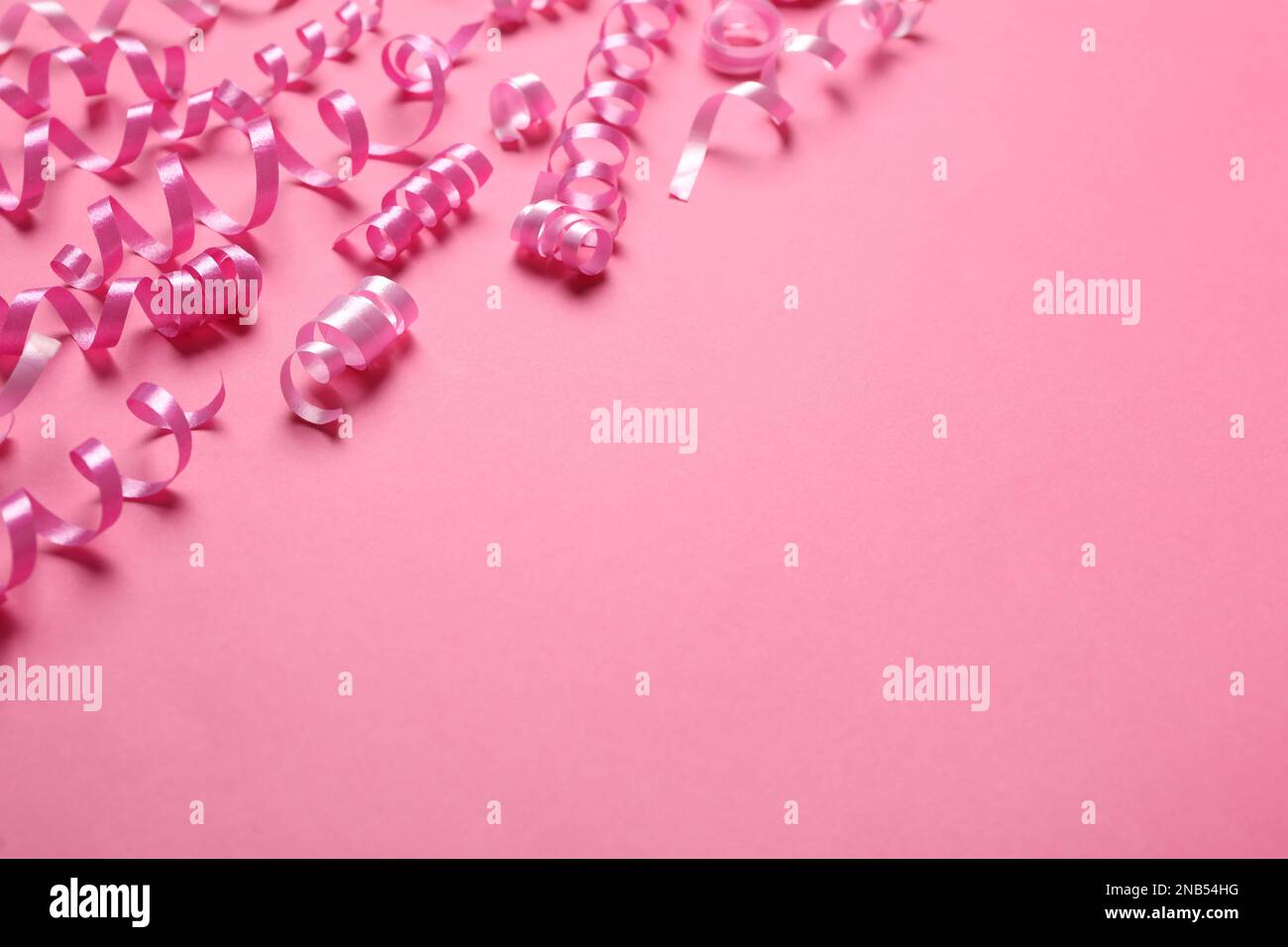 Shiny serpentine streamers on pink background, space for text Stock ...