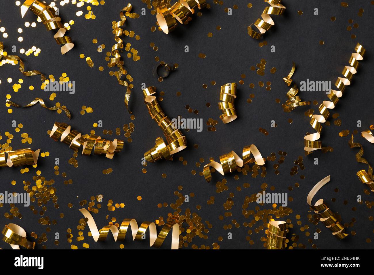 Shiny golden serpentine streamers and confetti on black background ...