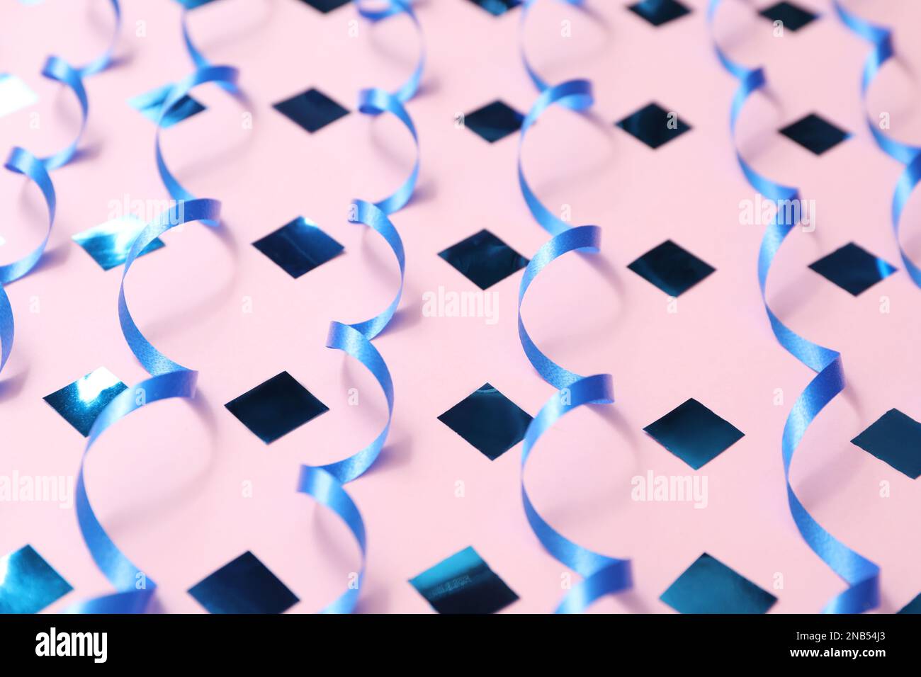 Shiny blue serpentine streamers and confetti on pink background ...