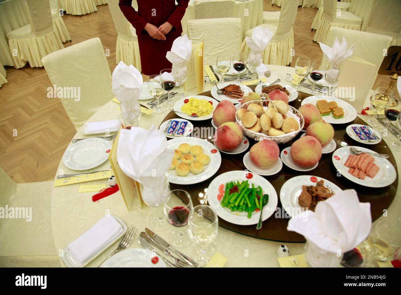 A waitress stand next to a table of food prepared for a National Day ...