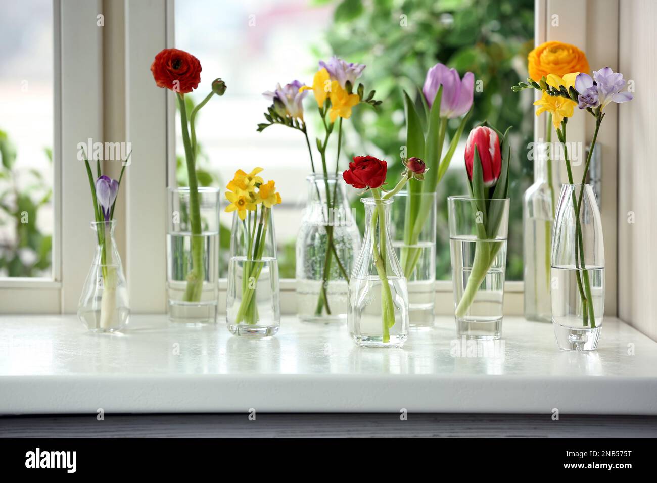 Beautiful spring flowers in glassware on window sill Stock Photo - Alamy