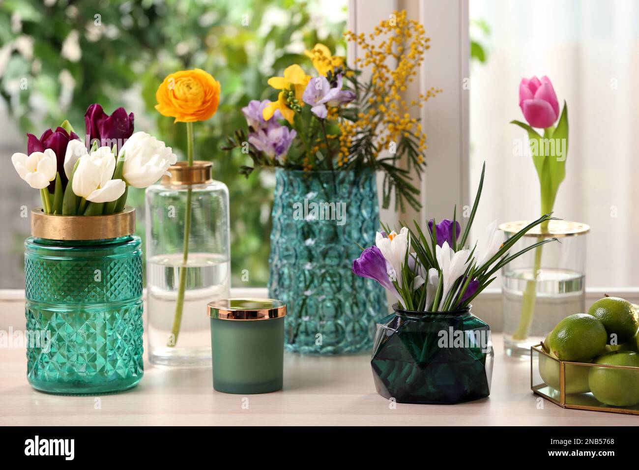 Different beautiful spring flowers and candle on window sill Stock ...