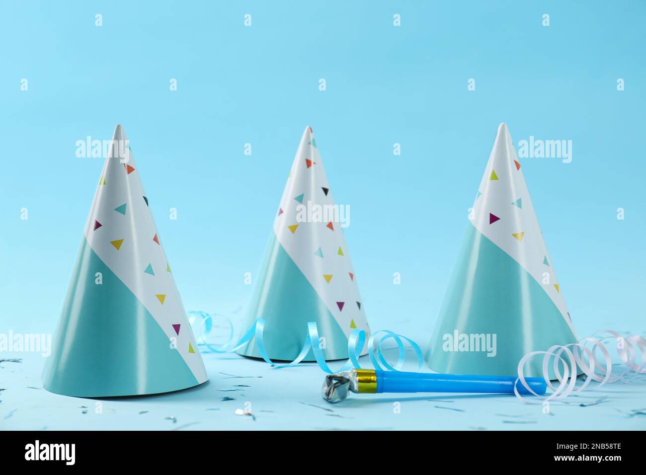 Bright party hats, horn, serpentine streamers and confetti on light ...