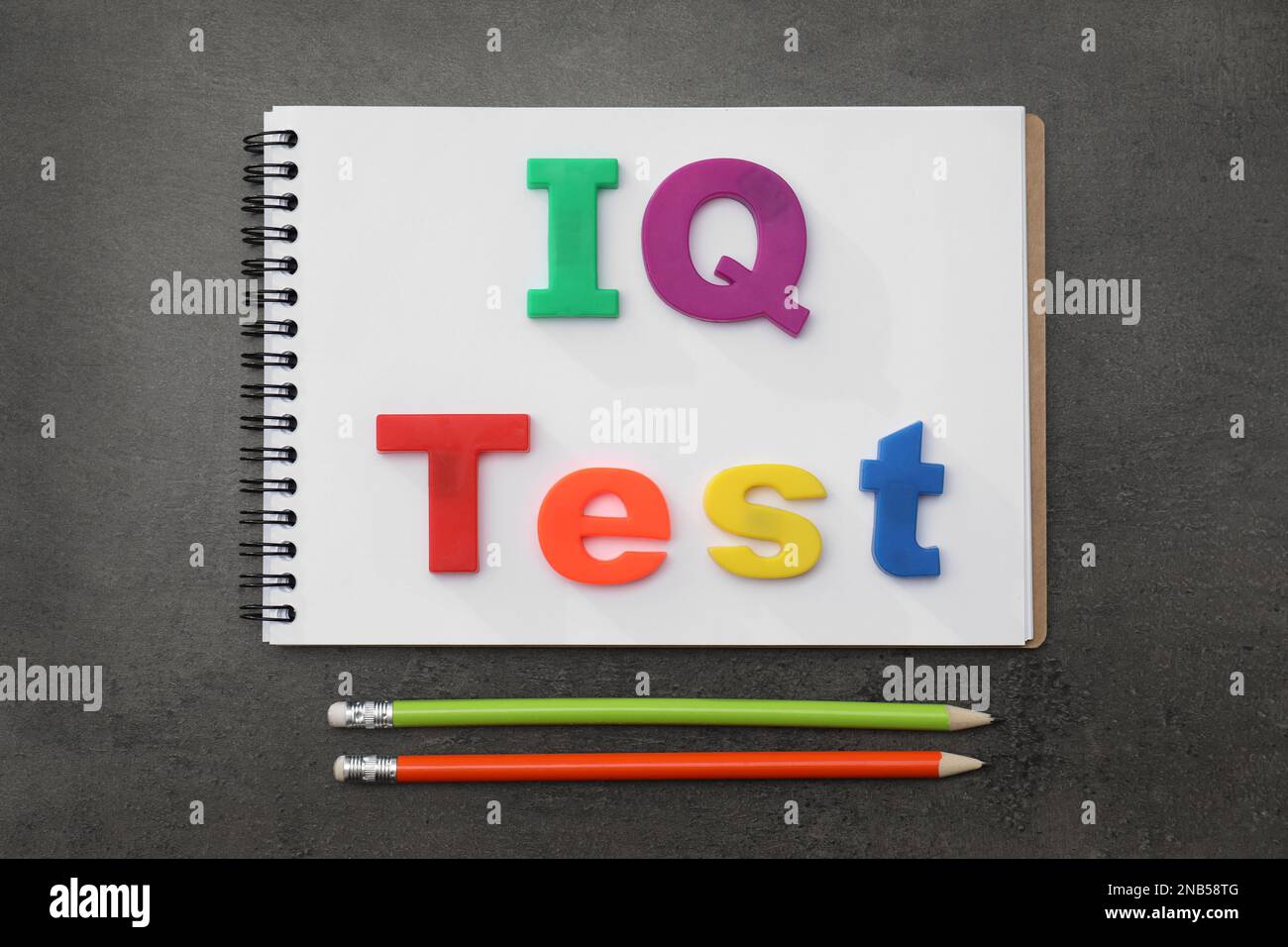 Notebook with words IQ Test made of magnets and pencils on black table ...