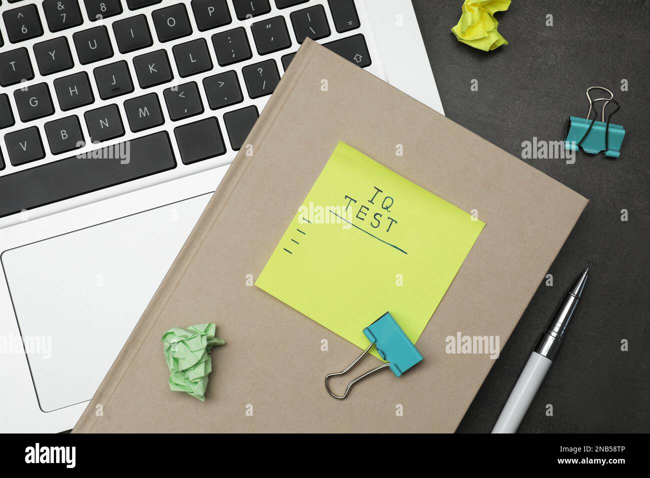 Sticky paper with words IQ Test, notebook and laptop on black table ...
