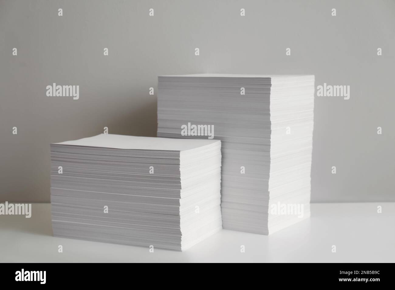 Stacks of paper sheets on white table Stock Photo - Alamy