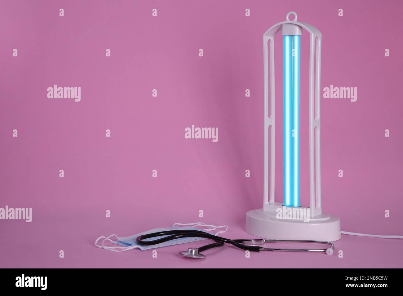 Ultraviolet lamp, medical masks and stethoscope on pink background ...