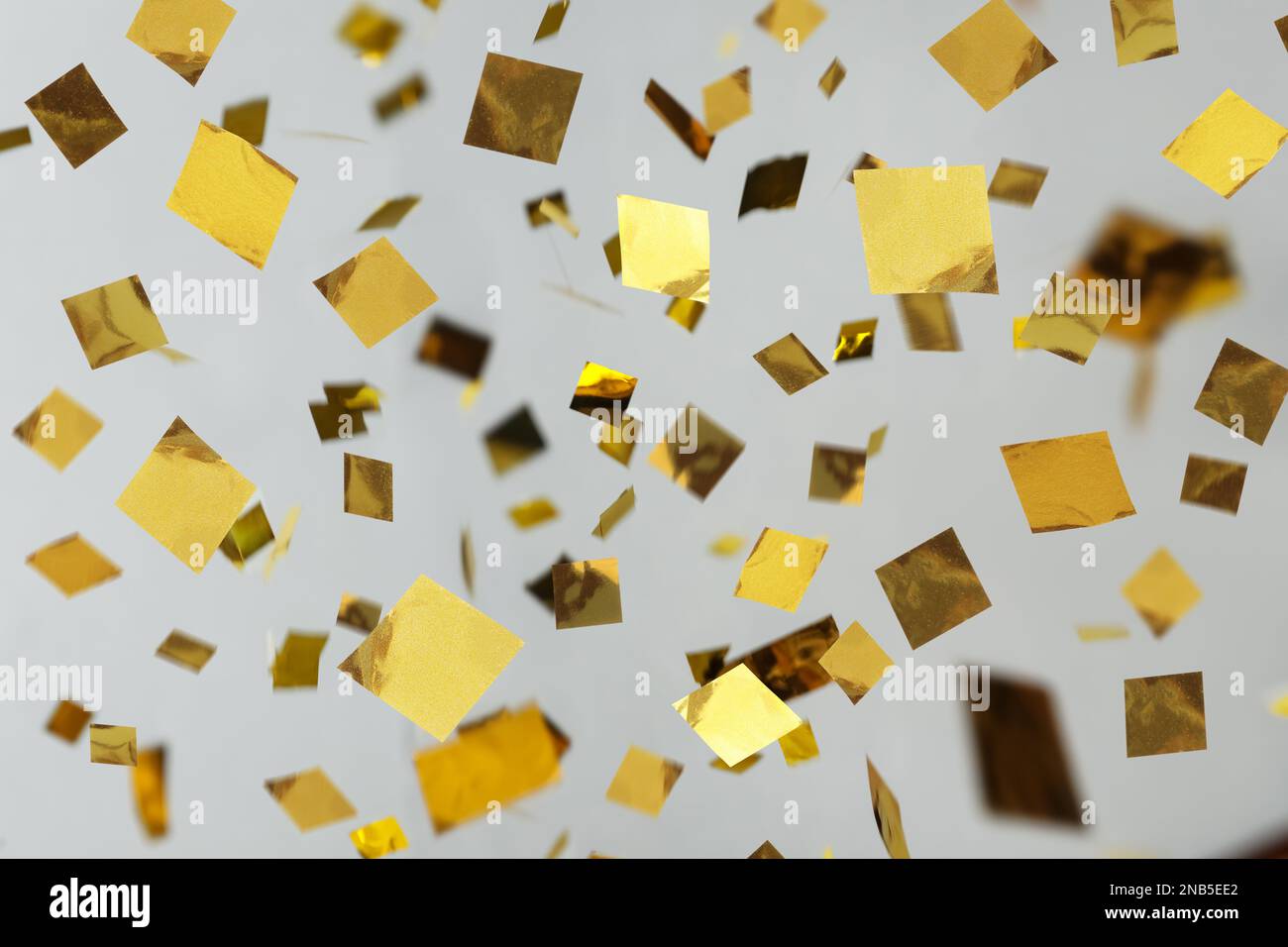 Shiny golden confetti falling down on light grey background Stock Photo ...