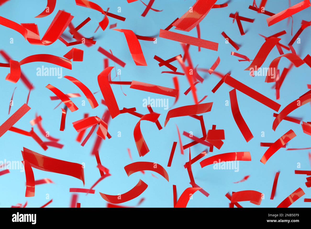 Shiny red confetti falling down on light blue background Stock Photo ...